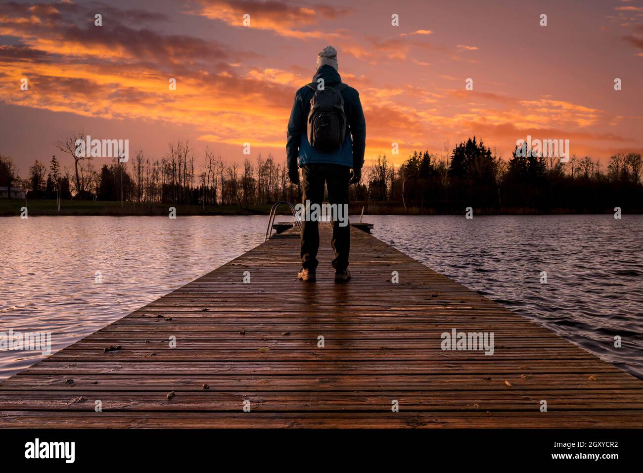 Silhouette of man standing on the lake wooden pier at sunset, human ...