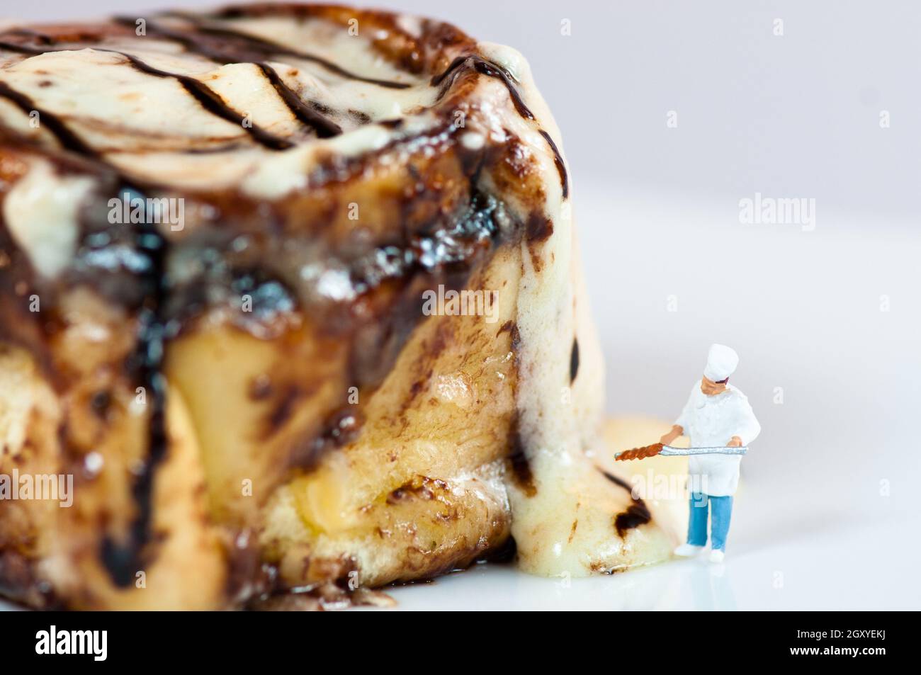 Miniature Chef with the giant Cinnamon roll Stock Photo - Alamy