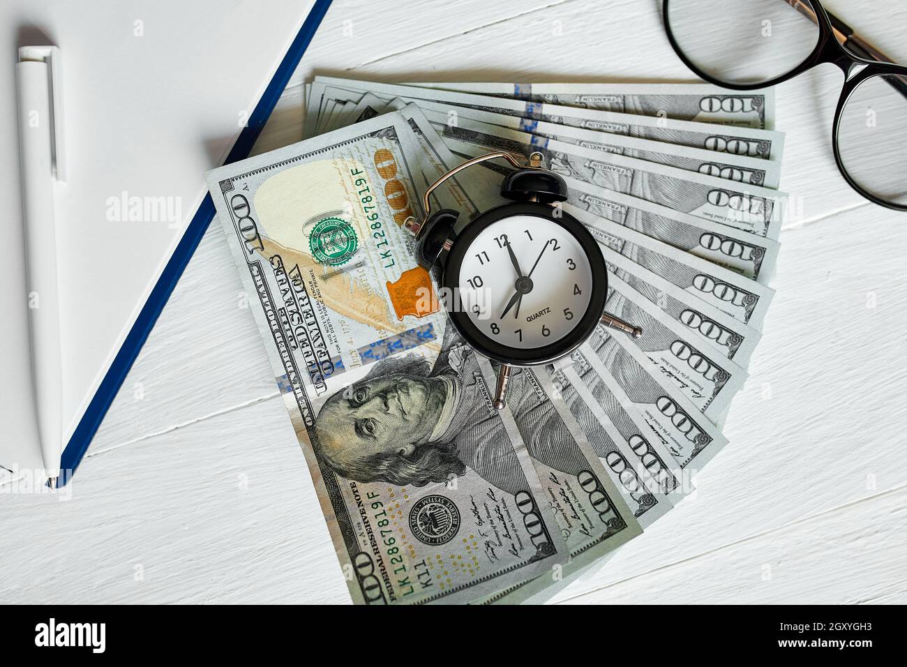 Top view flat lay of Alarm clock and money on white wooden background ...