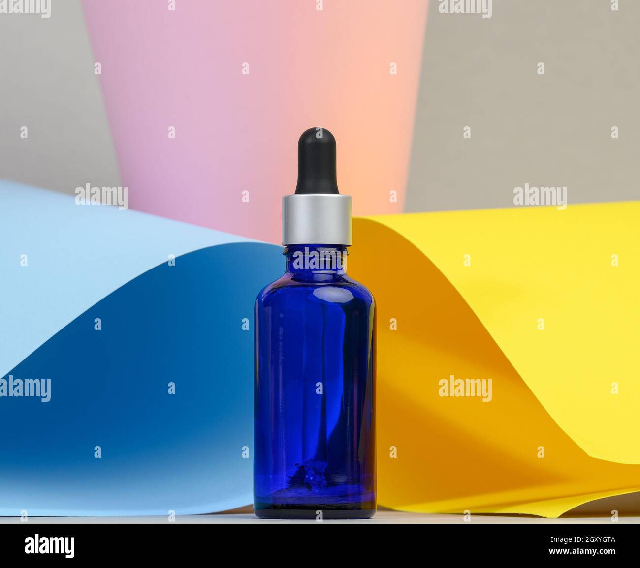 blue glass transparent bottle with a pipette on a colored background ...