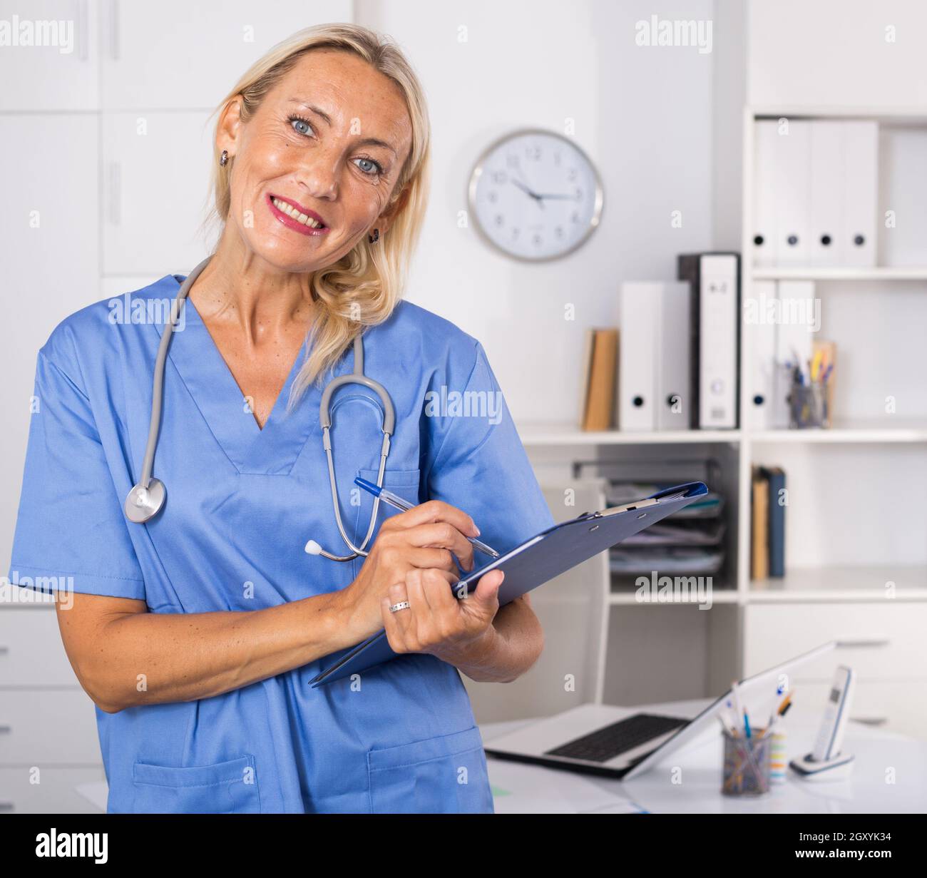 Female doctor writing notes on clipboard in clinic Stock Photo - Alamy