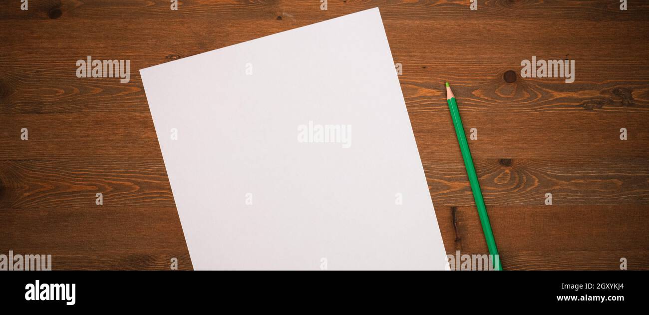 A blank white sheet and pencil for drawing on a wooden background with ...