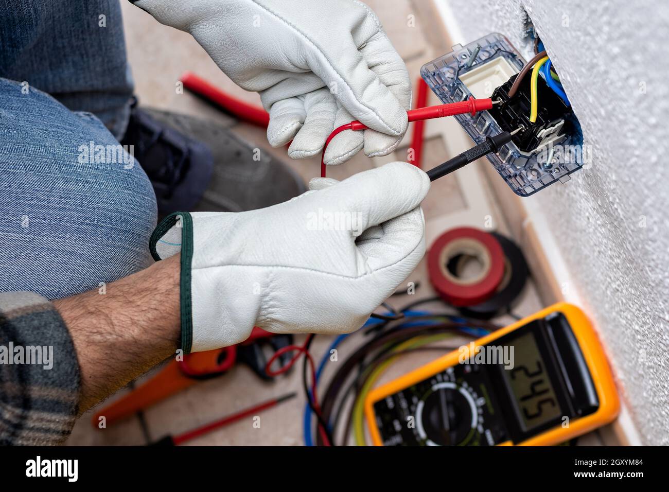 View from above. Electrician worker at work with the tester measures ...