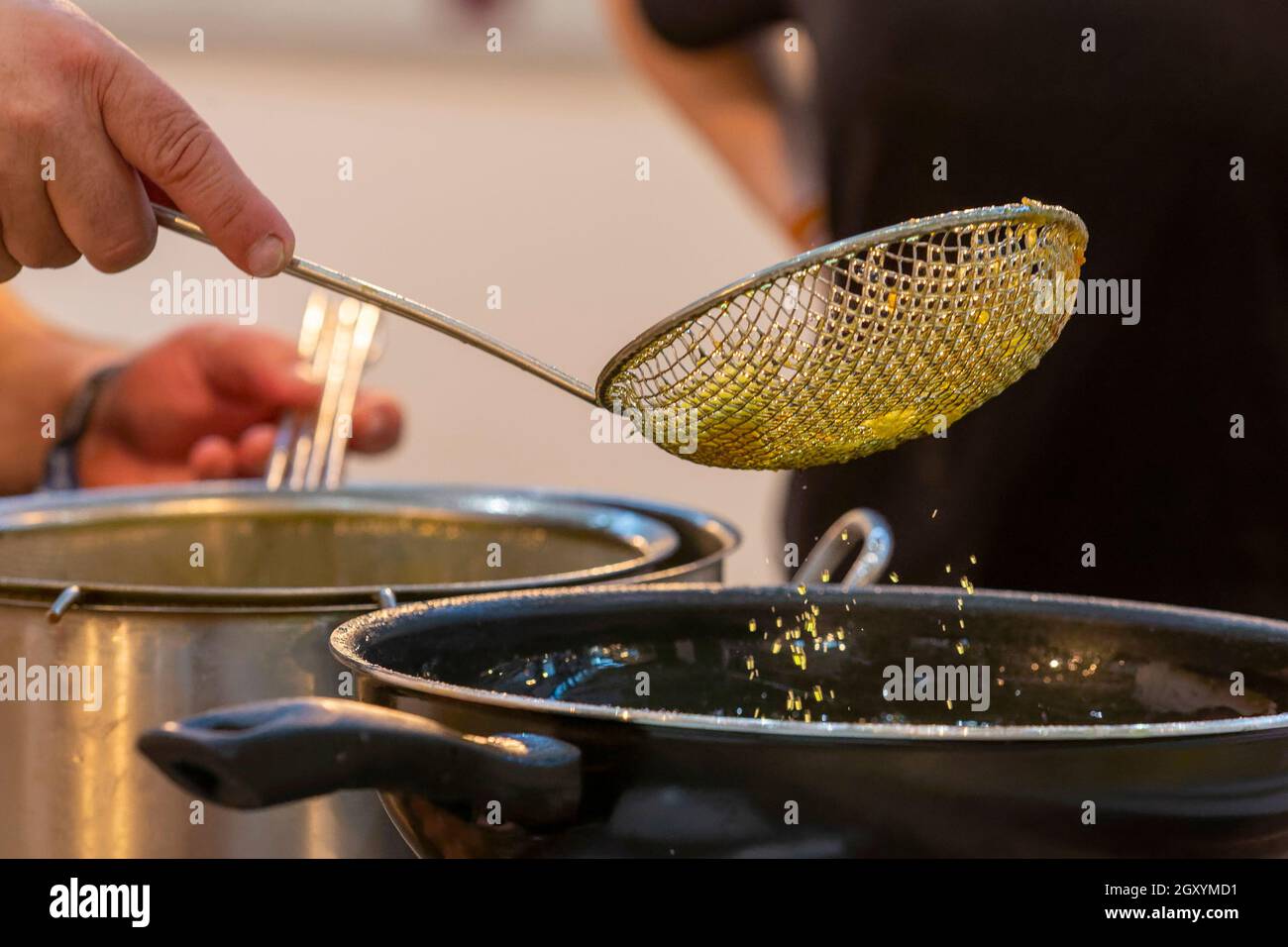 cook preparing and picking up freshly fried product with the frying pan ...