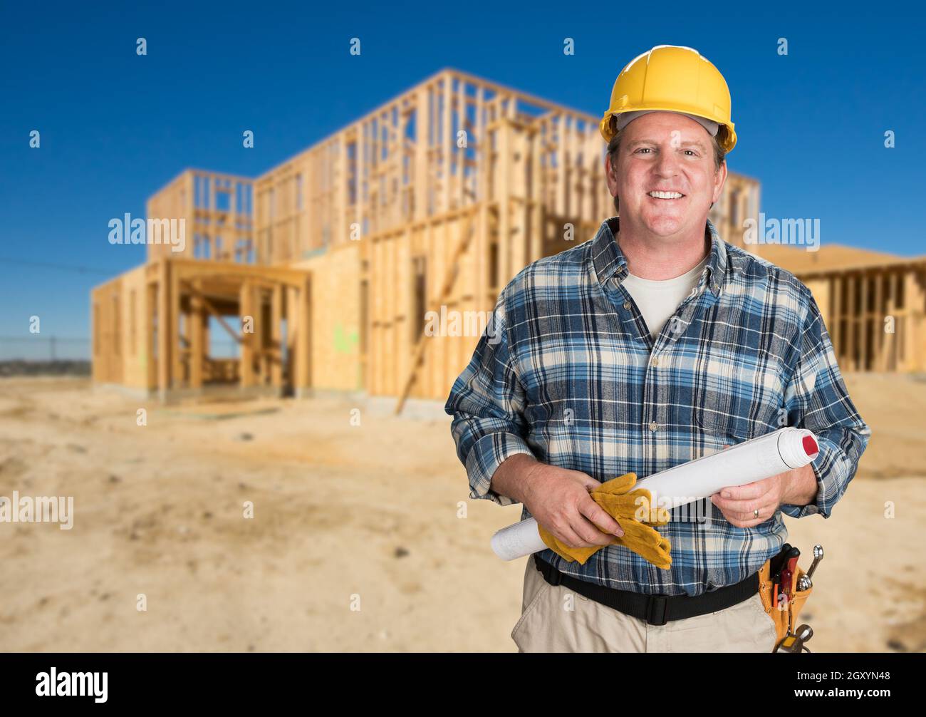 Contractor with Plans and Hard Hat In Front of New House Framing at ...