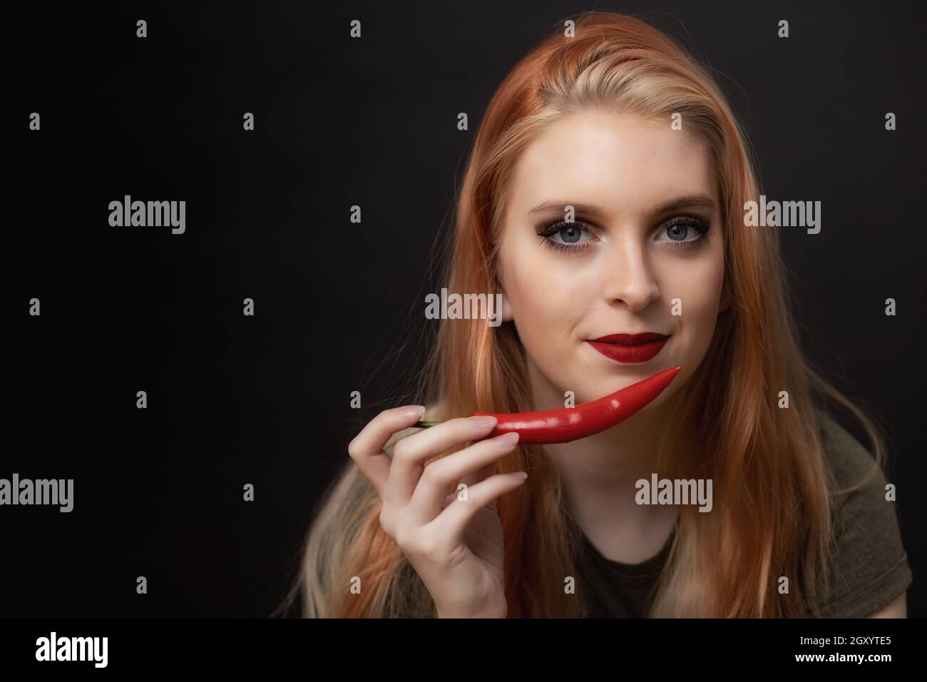 Front view portrait of attractive long hair young woman tasting chili ...