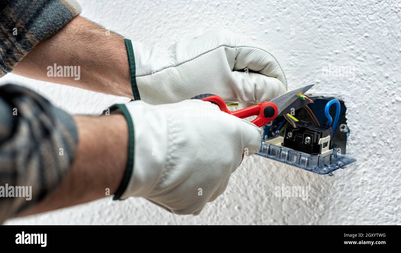 Electrician worker at work with scissors prepares the electrical cables ...