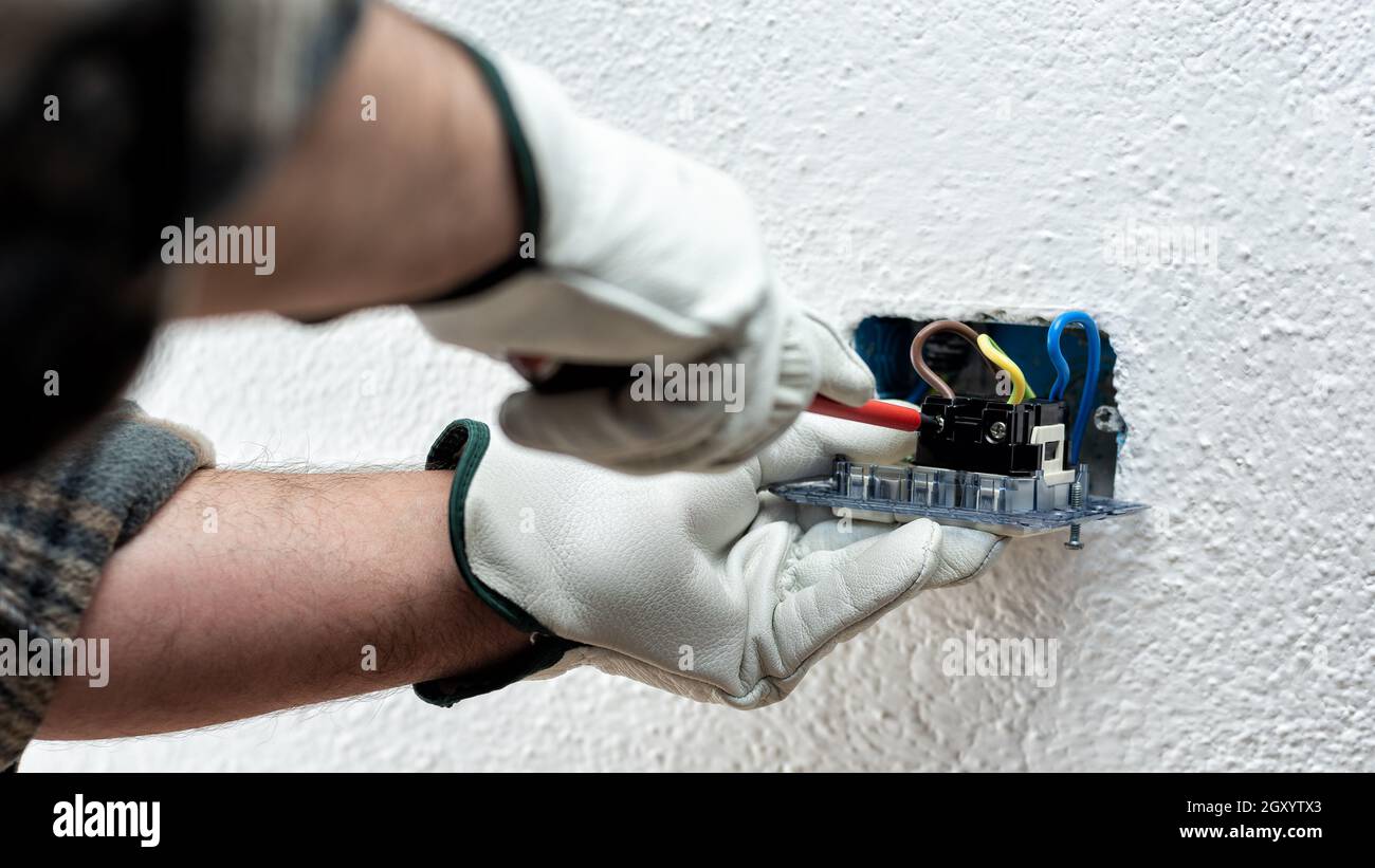 Electrician worker with screwdriver fixes electrical cables in the ...
