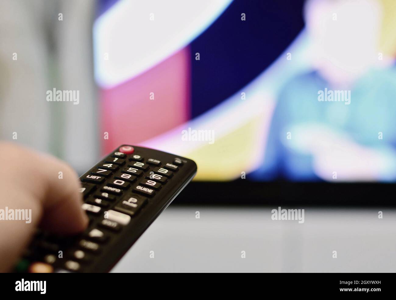 Close up of a hand holding television remote control which switching ...