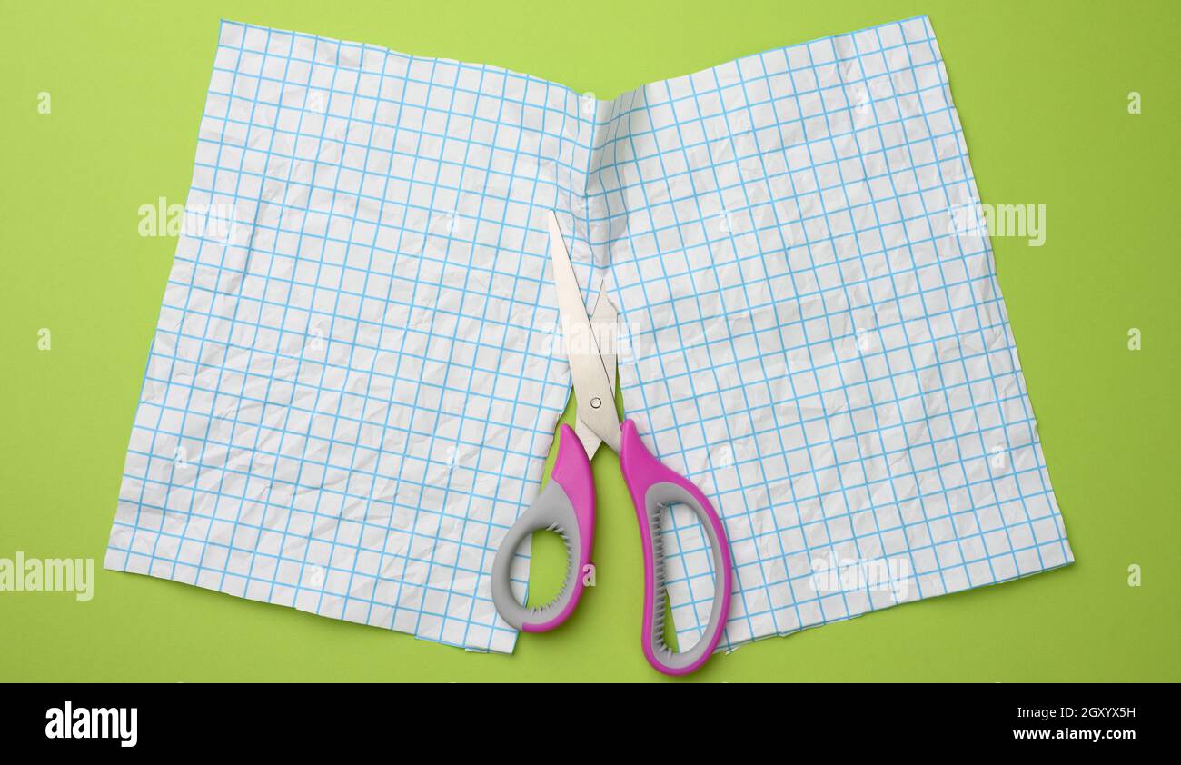 a sheet of white paper cut in half with scissors in a blue box on a ...