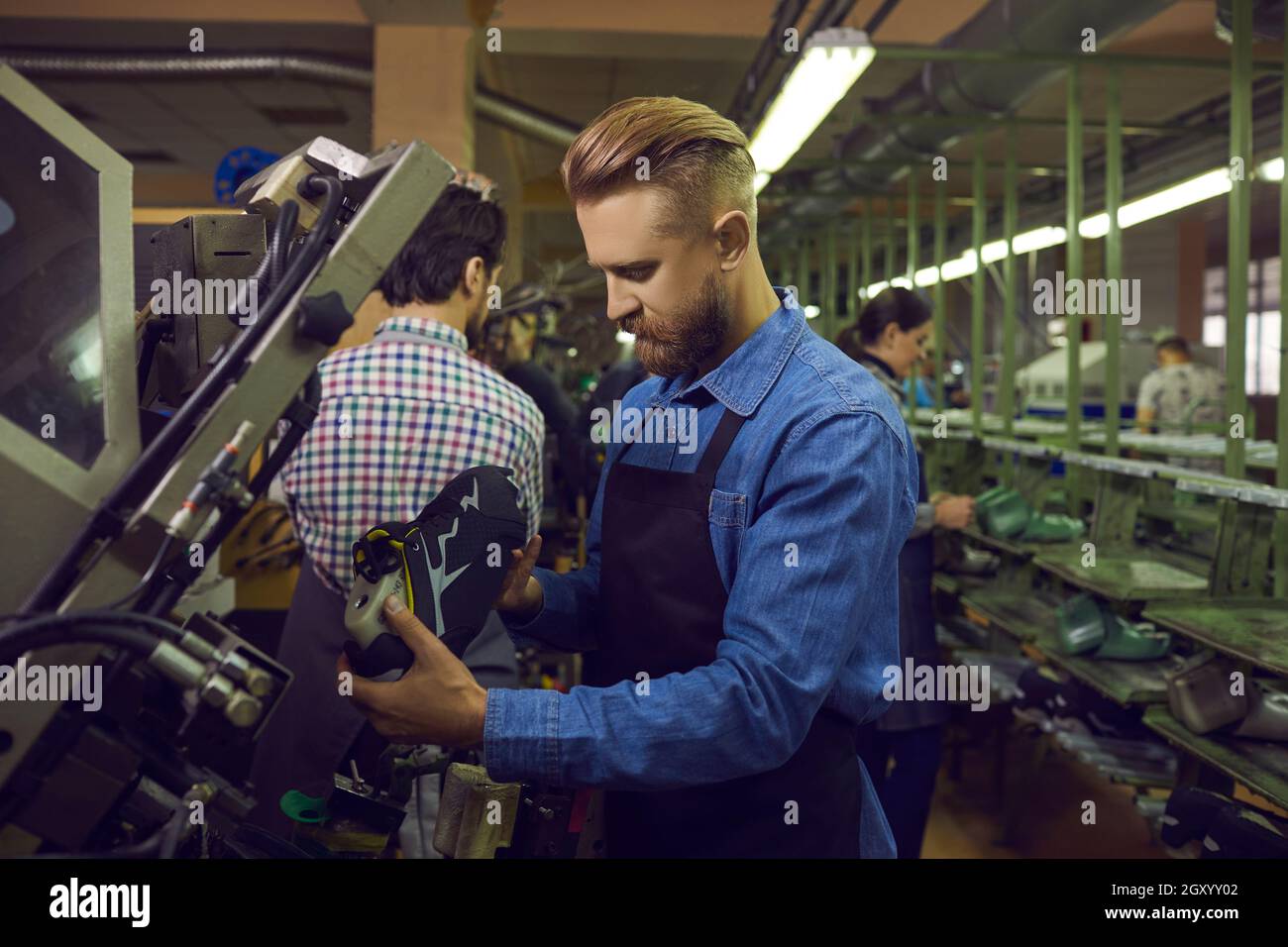 Male worker using industrial press while making new sneakers at ...