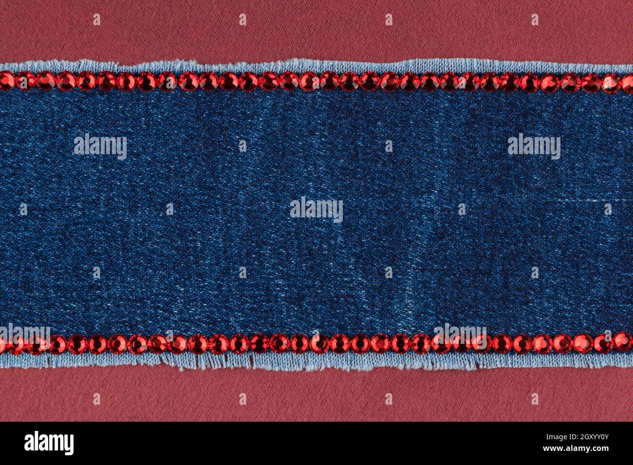 Fashionable texture, jeans and red rhinestones on a red silk, with ...