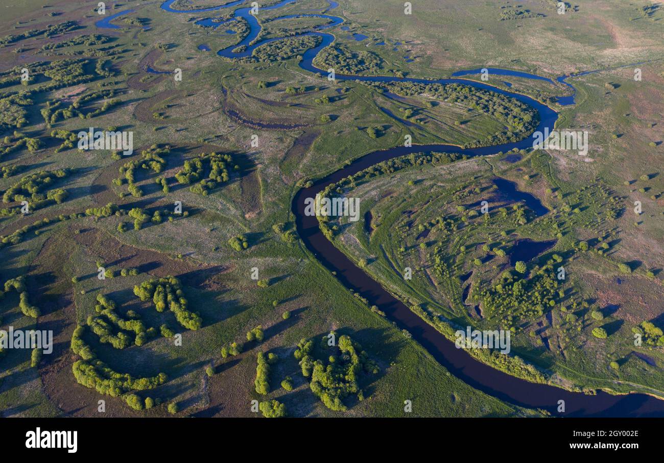 Aerial view of winding river bed with ducts. Flying above swampy plain ...