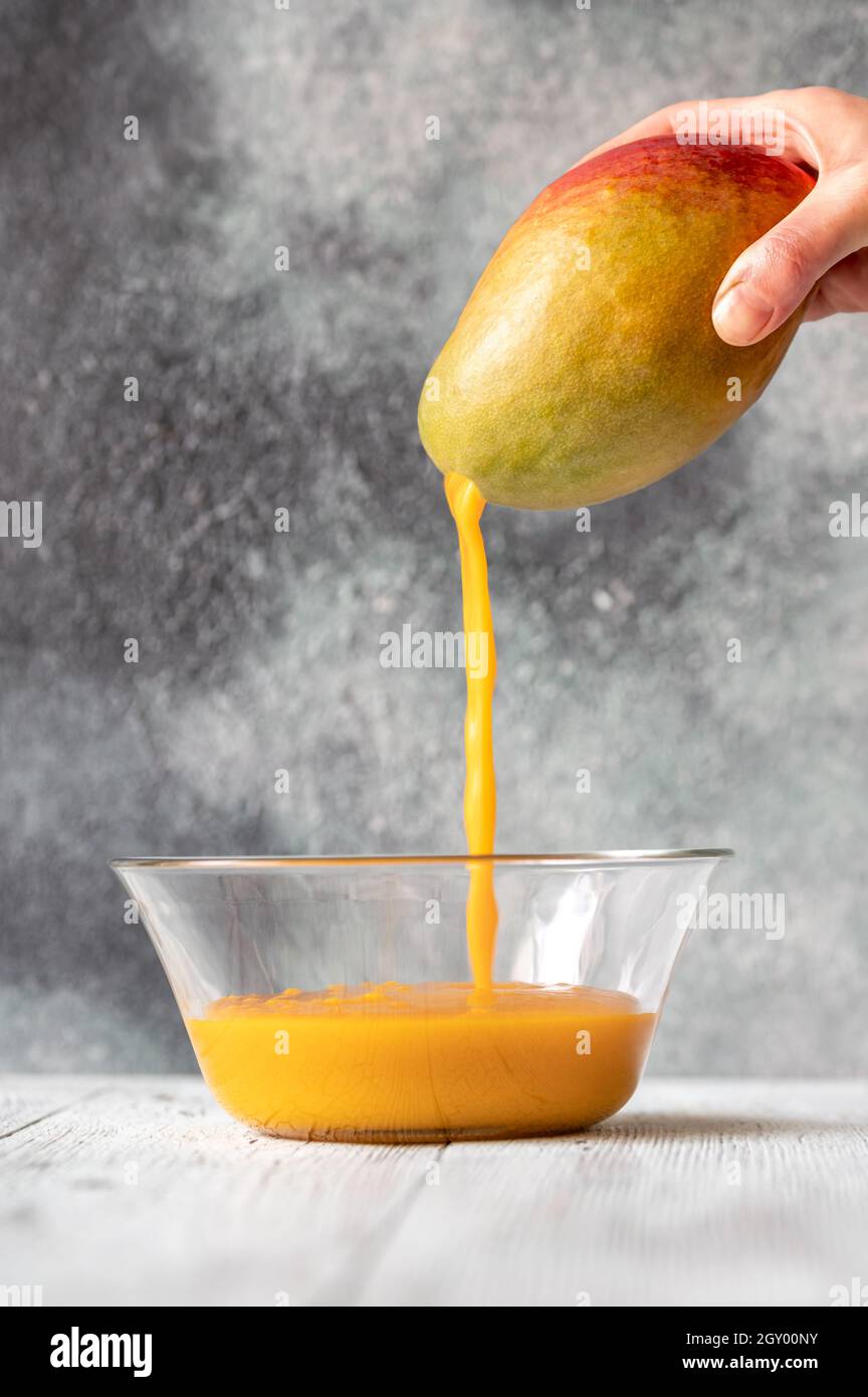 Fresh mango juice pouring into the glass bowl Stock Photo - Alamy