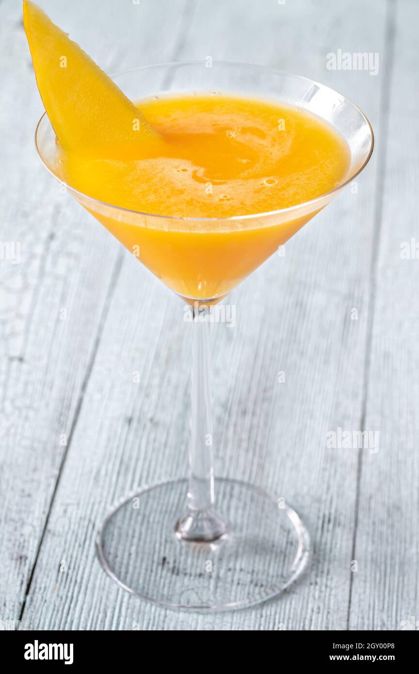 Glass of Apricot Mango Cocktail garnished with slice of fresh mango ...