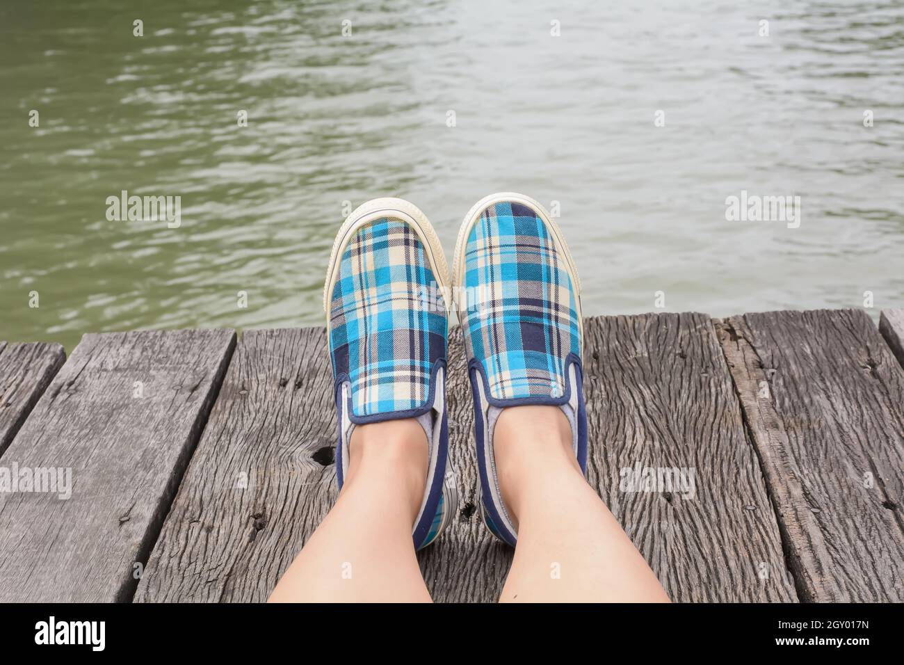 Girl wearing canvas sneakers sitting on the wooden bridge Stock Photo ...
