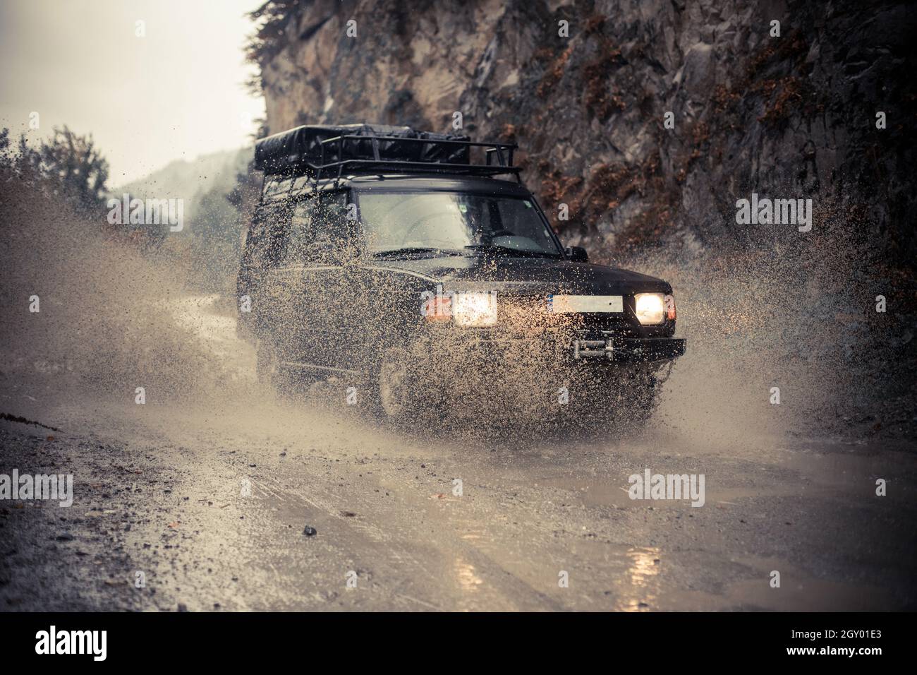 A 4x4 car speeding through a puddle and splashing water Stock Photo - Alamy