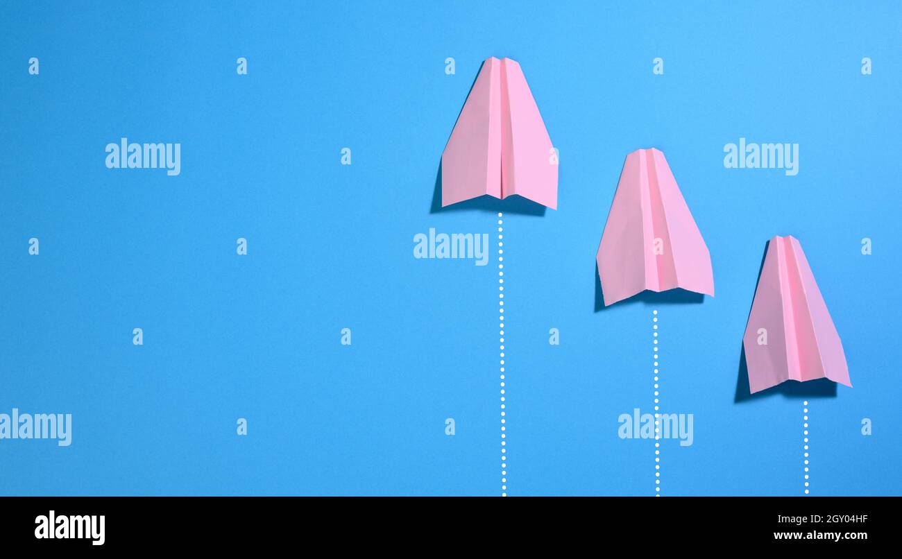 three pink paper airplanes on a blue background. The concept of ...