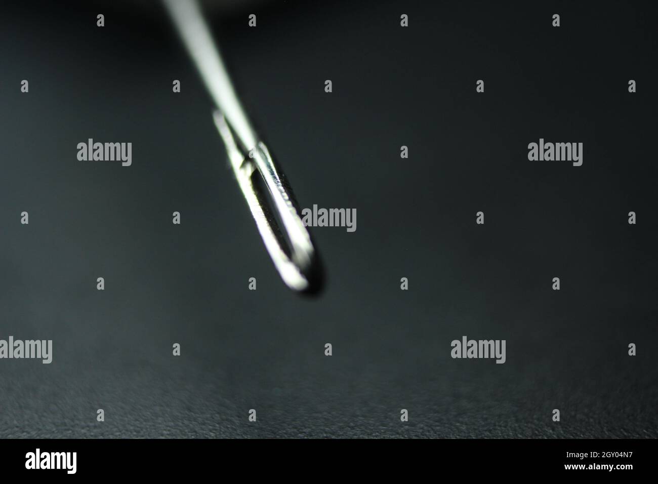 Macro photograph of sewing needle. Small needle with empty eyelet ...