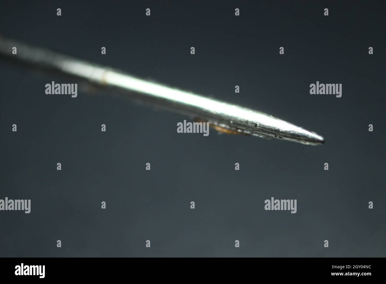 Macro photograph of sewing needle. Small needle with empty eyelet ...