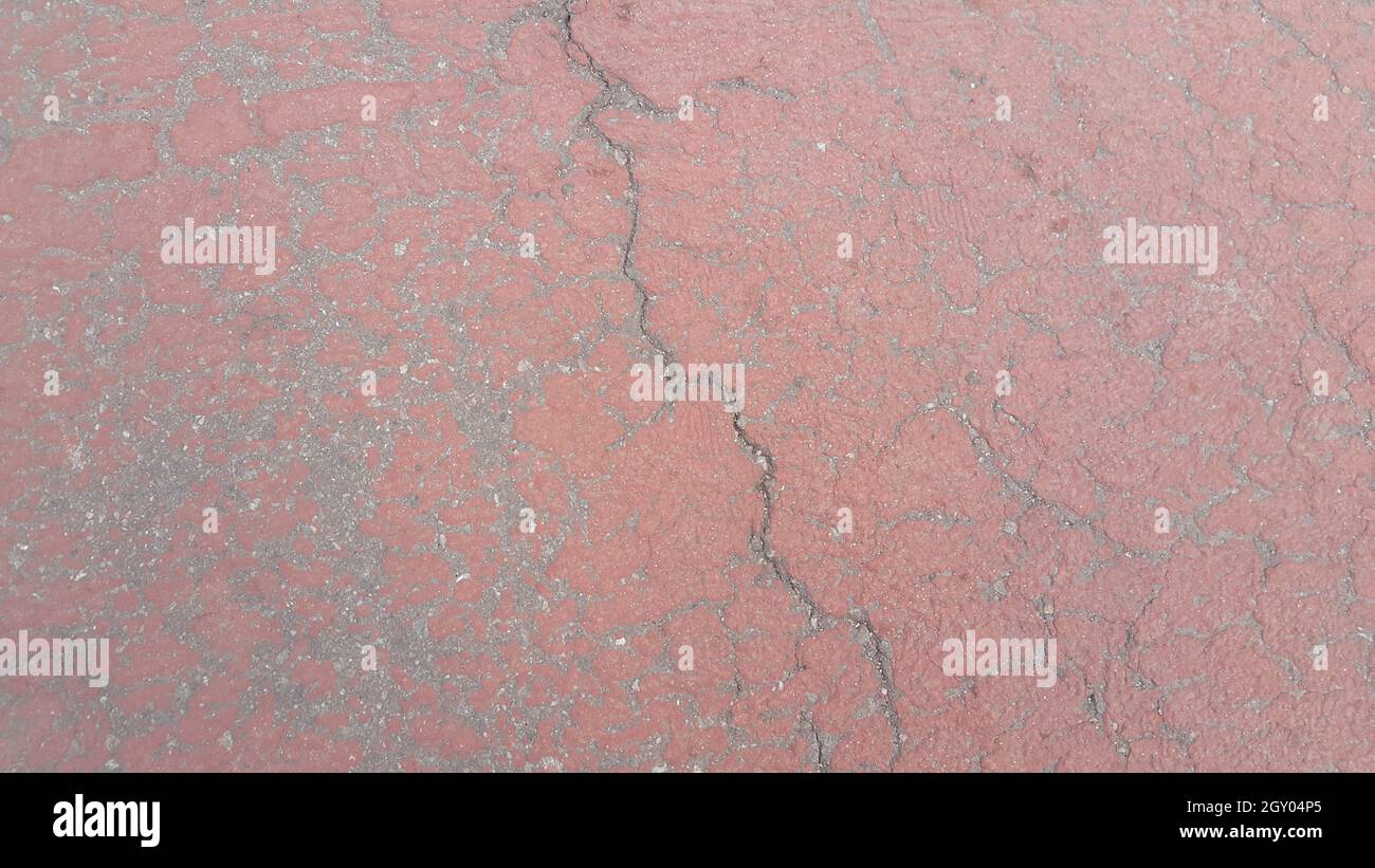 Red colored damaged road or paved pathway with crackes of different ...