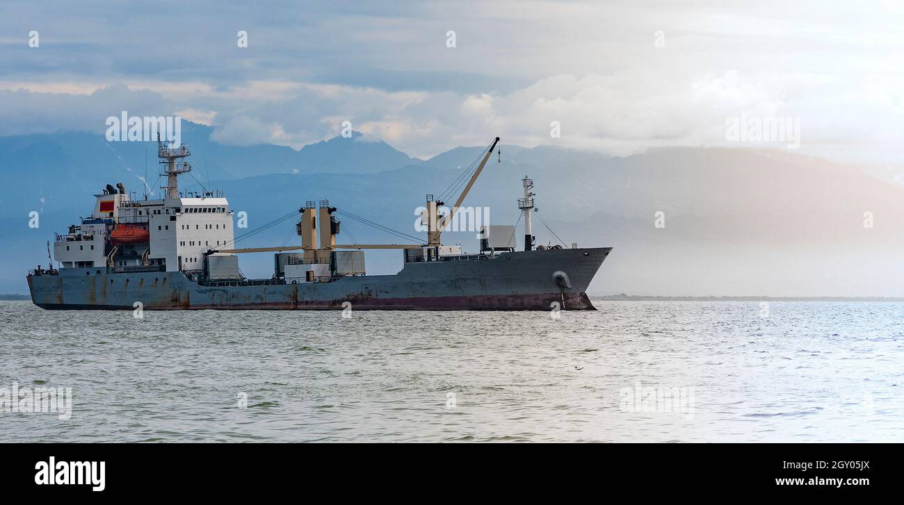 The Large cargo container ship sailing against the volcano Stock Photo ...