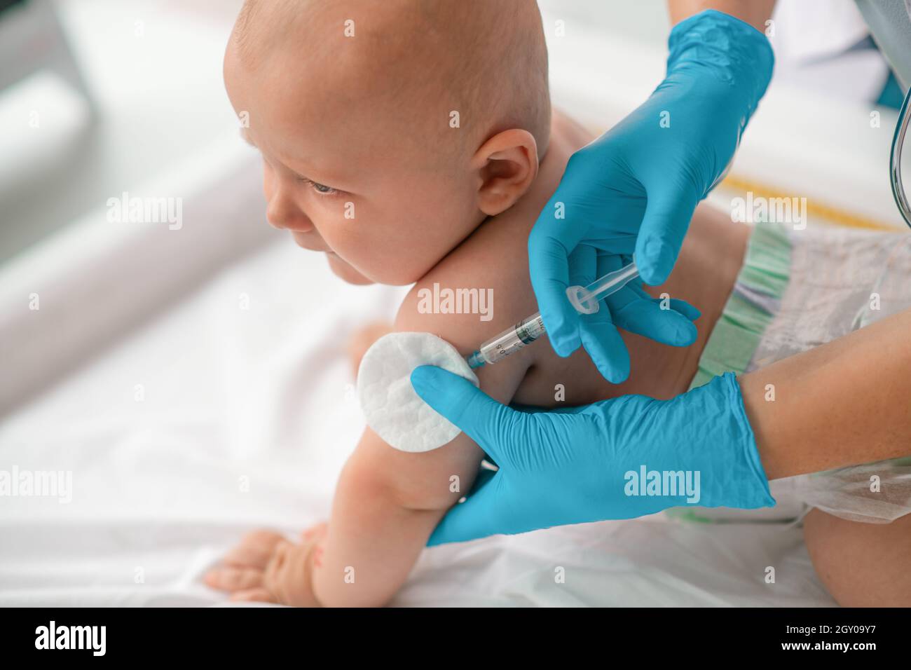 Calm cute newborn child getting an injection Stock Photo - Alamy