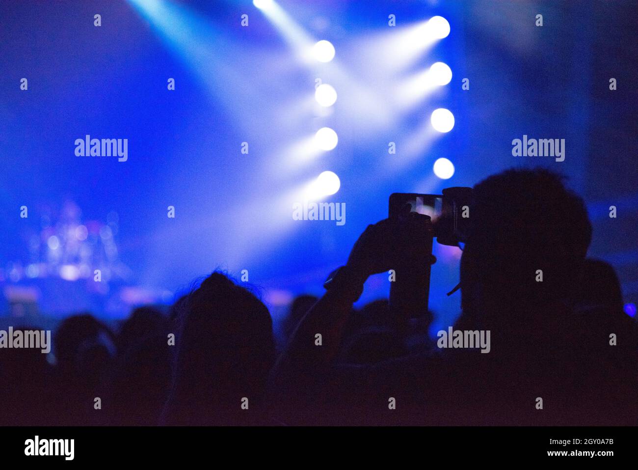 Hand holding smart phone at live music festival. Concert stage lights ...