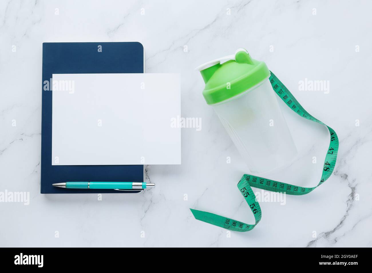 Blank white paper note and fitness equipments on white marble ...