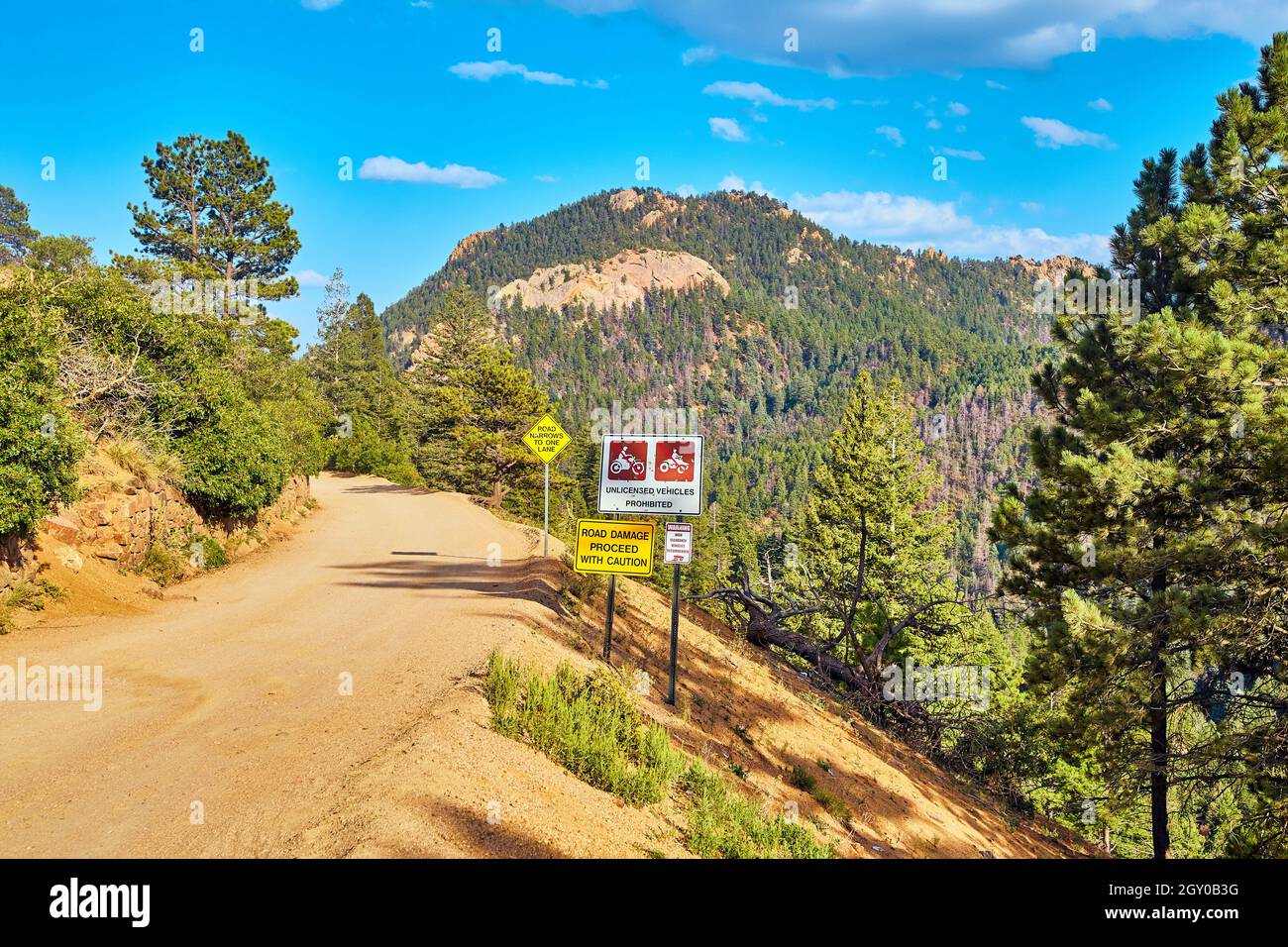 Dangerous dirt road path in mountains with warning signs proceed with ...