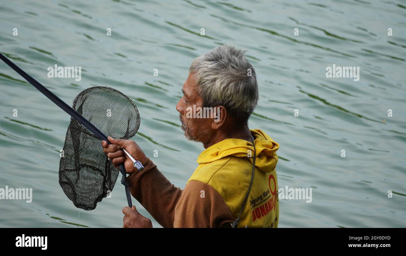 An old asian man holding a net Stock Photo - Alamy