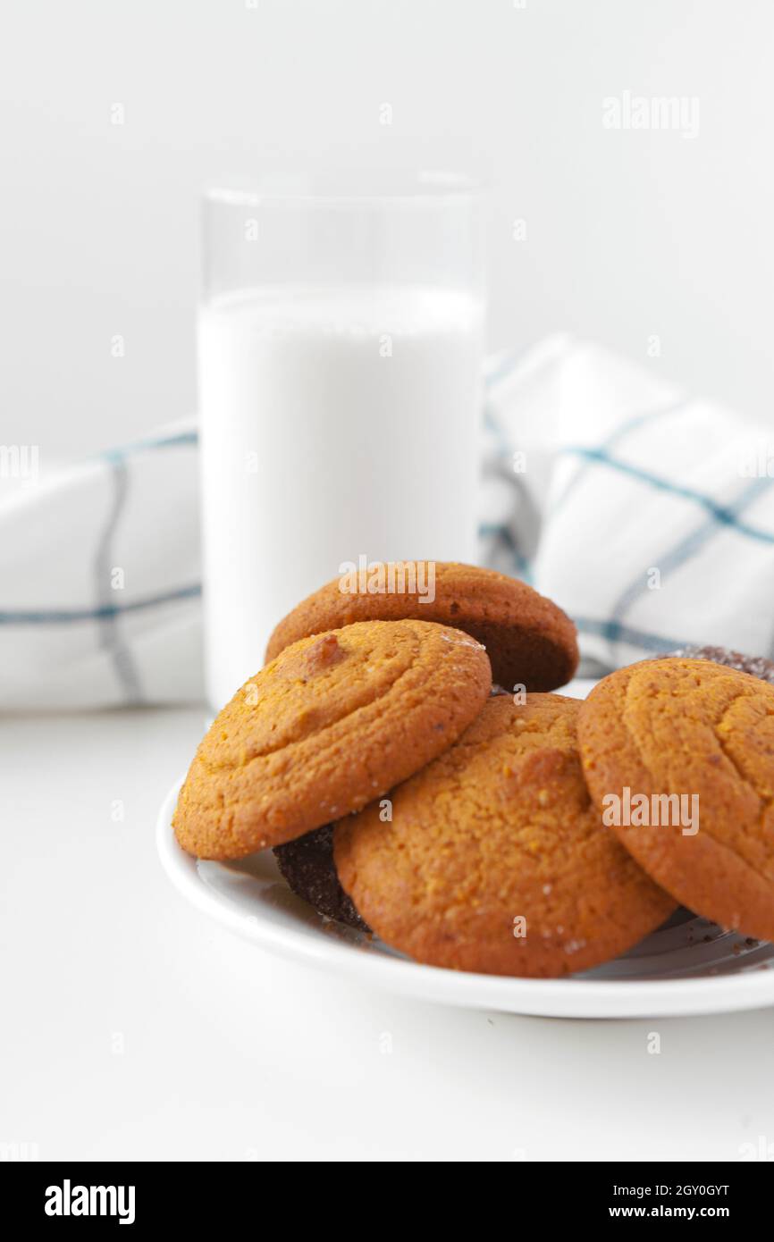 Milk glass and biscuit cookies with kitchen cloth on light background ...