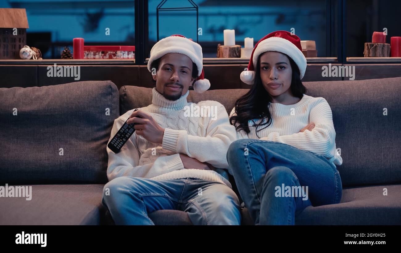 African american man watching movie with bored girlfriend in santa hat ...
