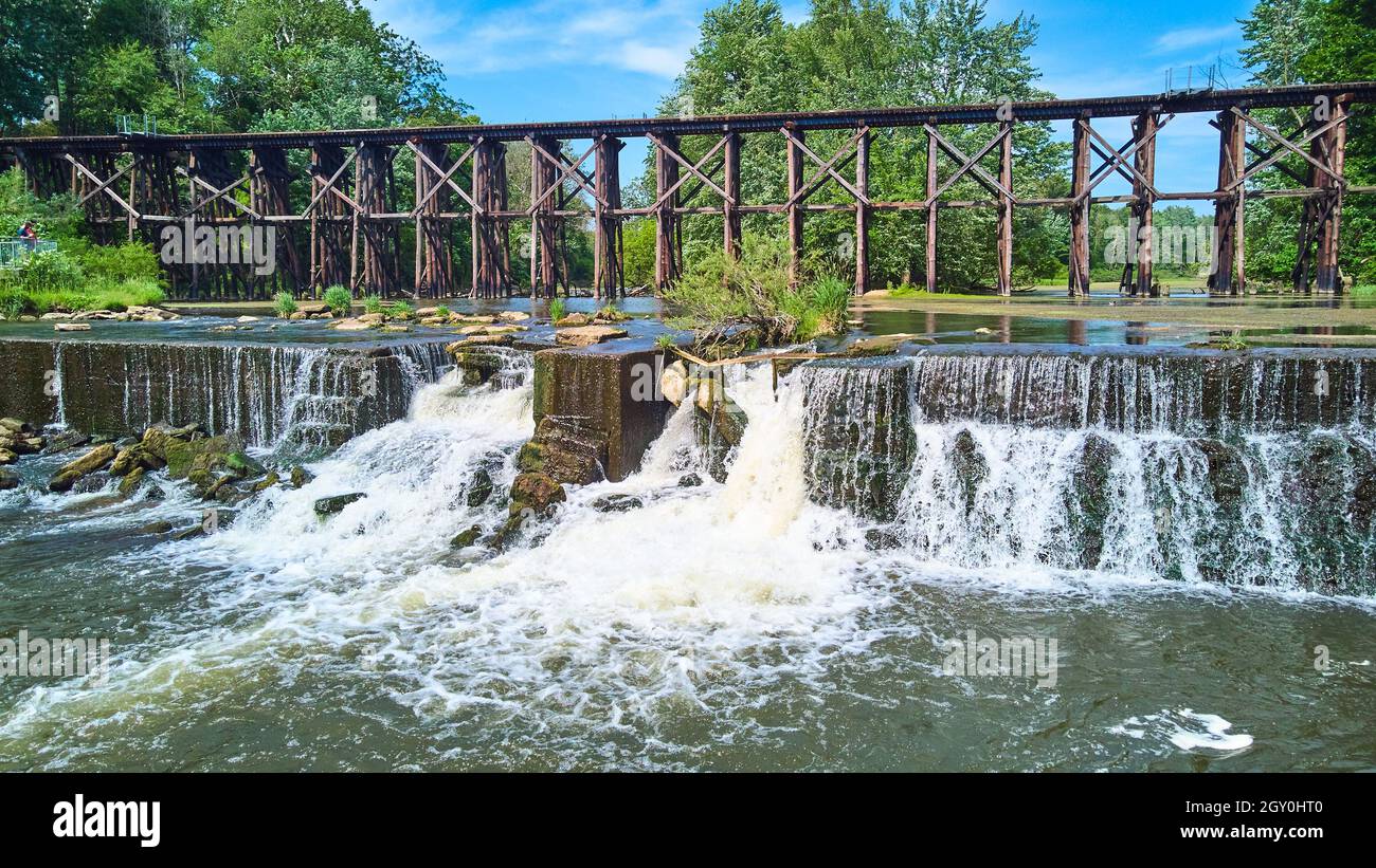 Manmade dam creating waterfalls with railroad wood bridge in background ...