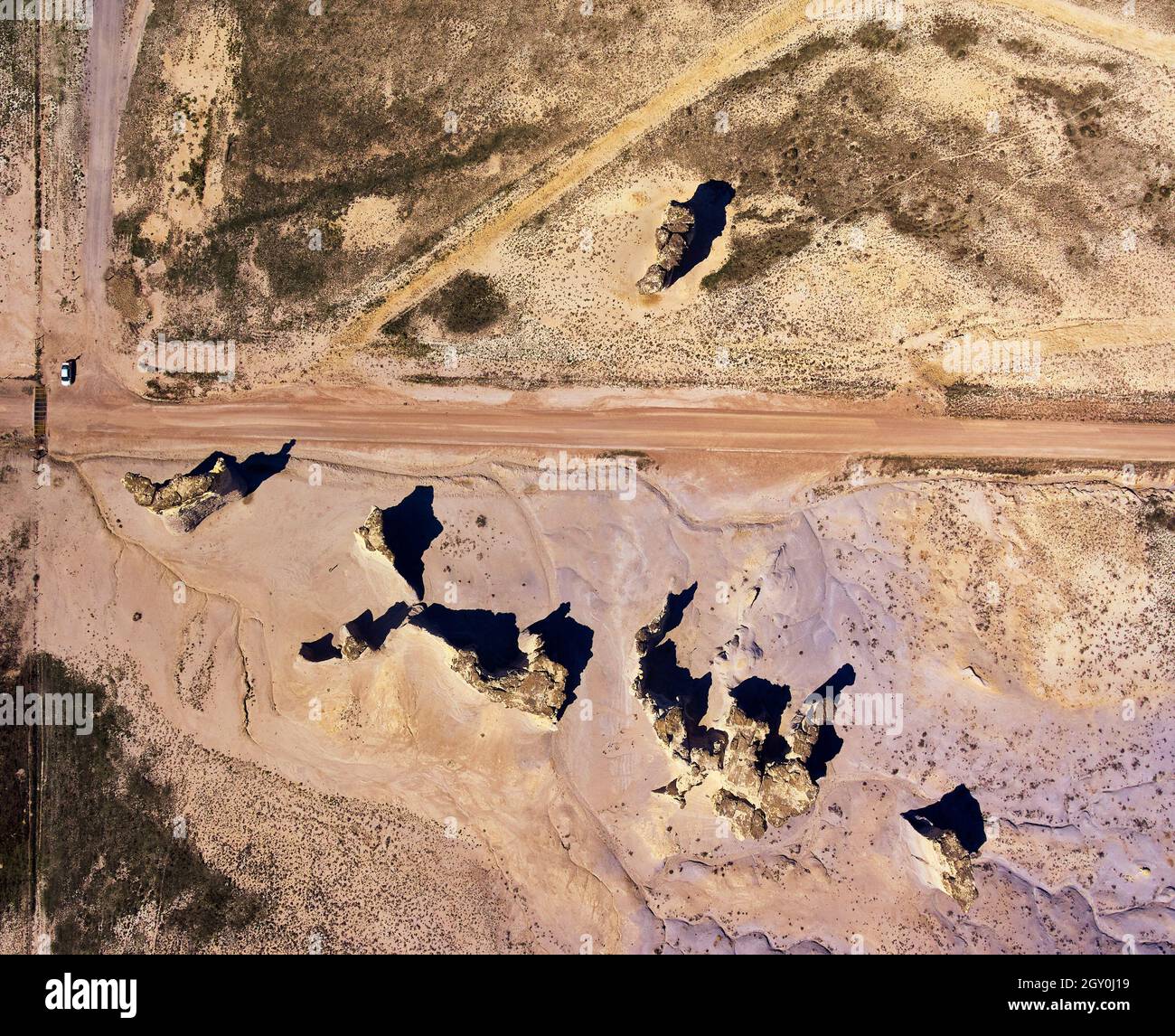 Aerial view from above of desert with dirt road and obelisk rock ...