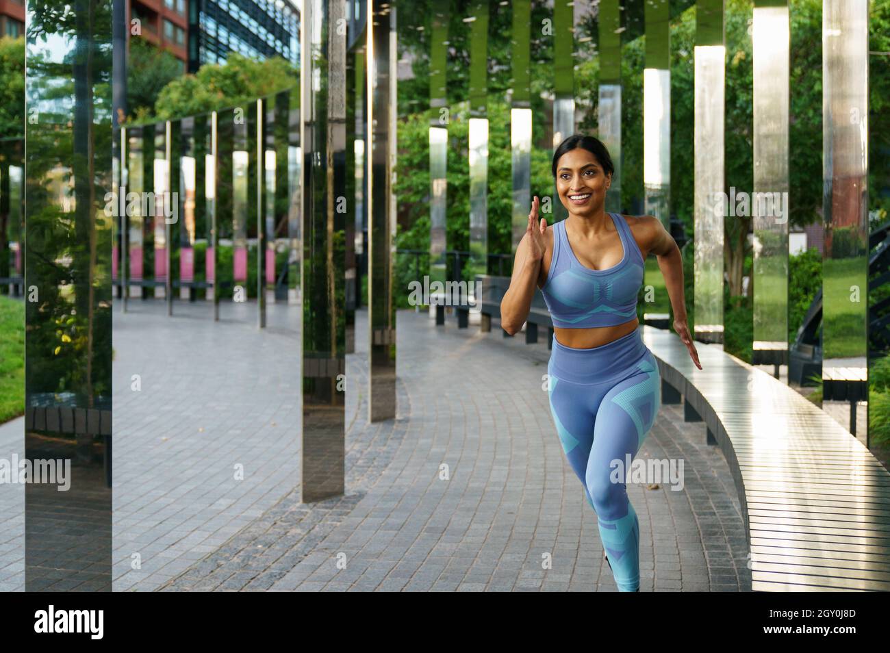 Woman in a grey outfit running in urban setting Stock Photo - Alamy