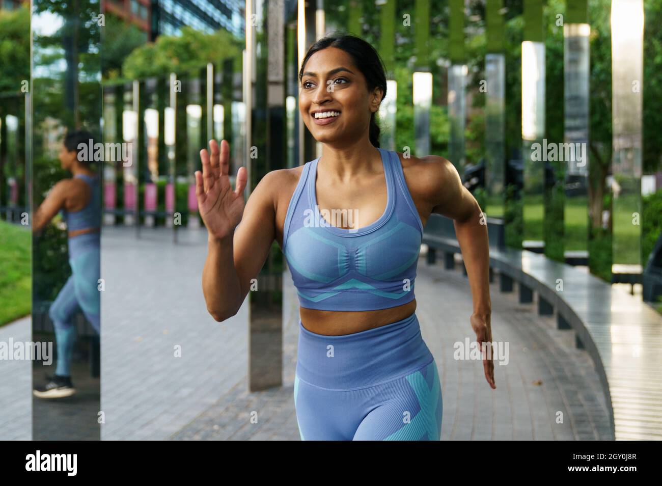 Woman in a grey outfit running in urban setting Stock Photo - Alamy