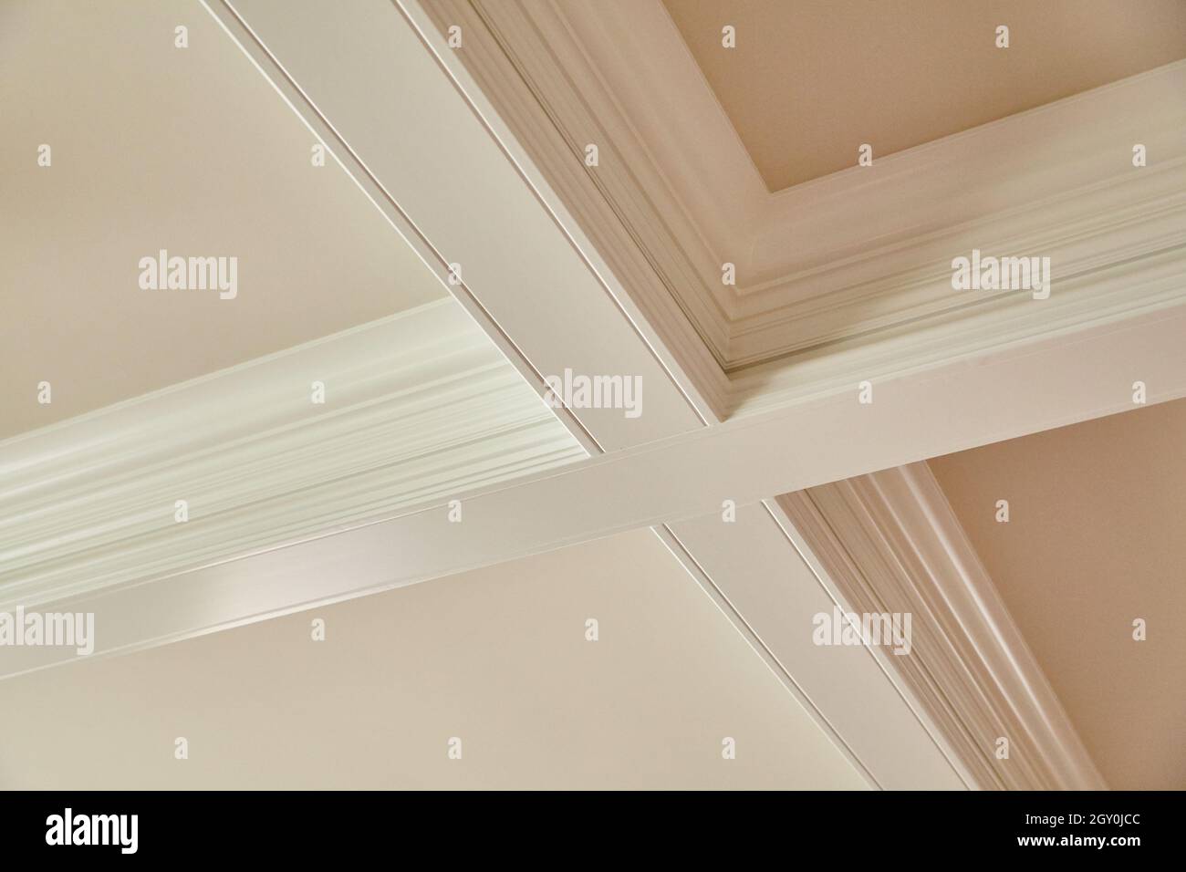 White crown molding on the ceiling forms a cross on an off white ...