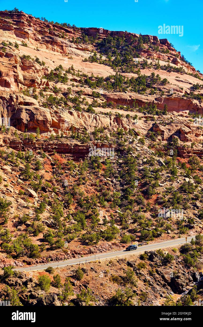Vertical of road cutting through the mountains with car for perspective ...