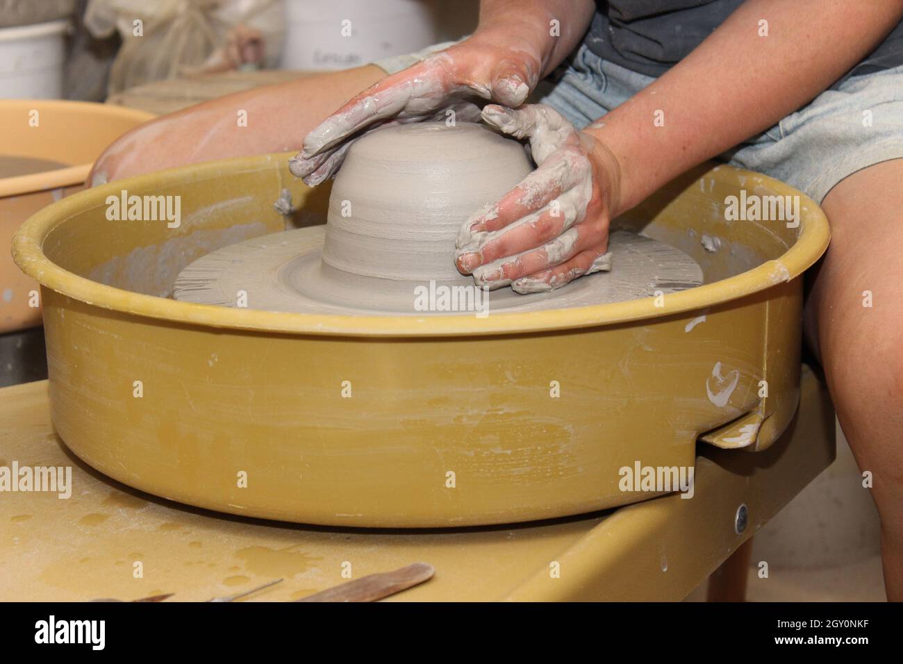 Working with clay in a pottery studio throwing a pot on the potter's ...