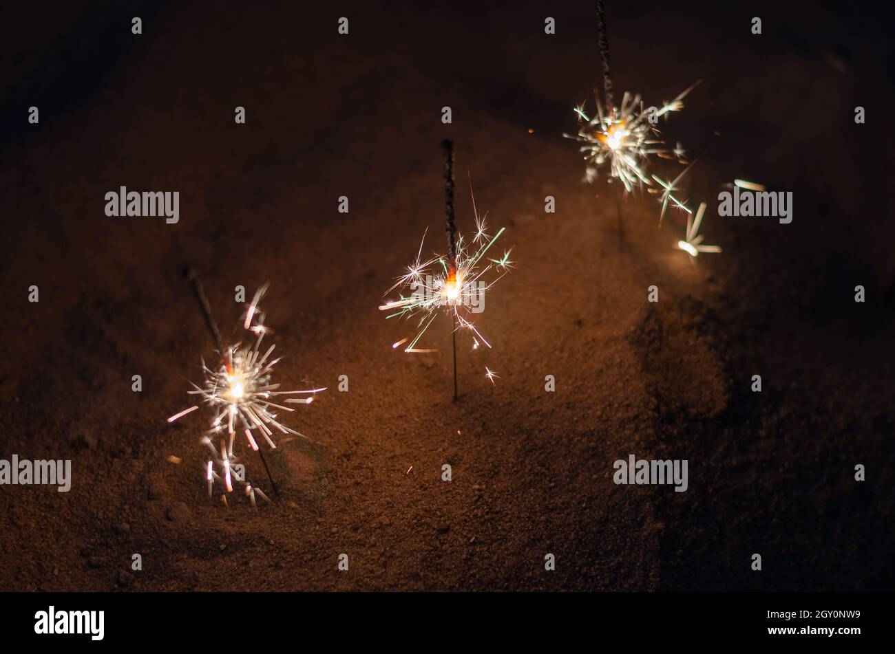 Beach sand at night with Bengal lights. Sparks of bright Bengal lights ...