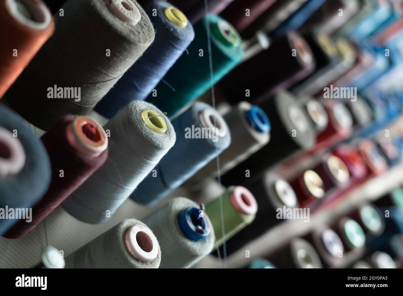 Sewing threads of different colors are installed on a metal wall and ...