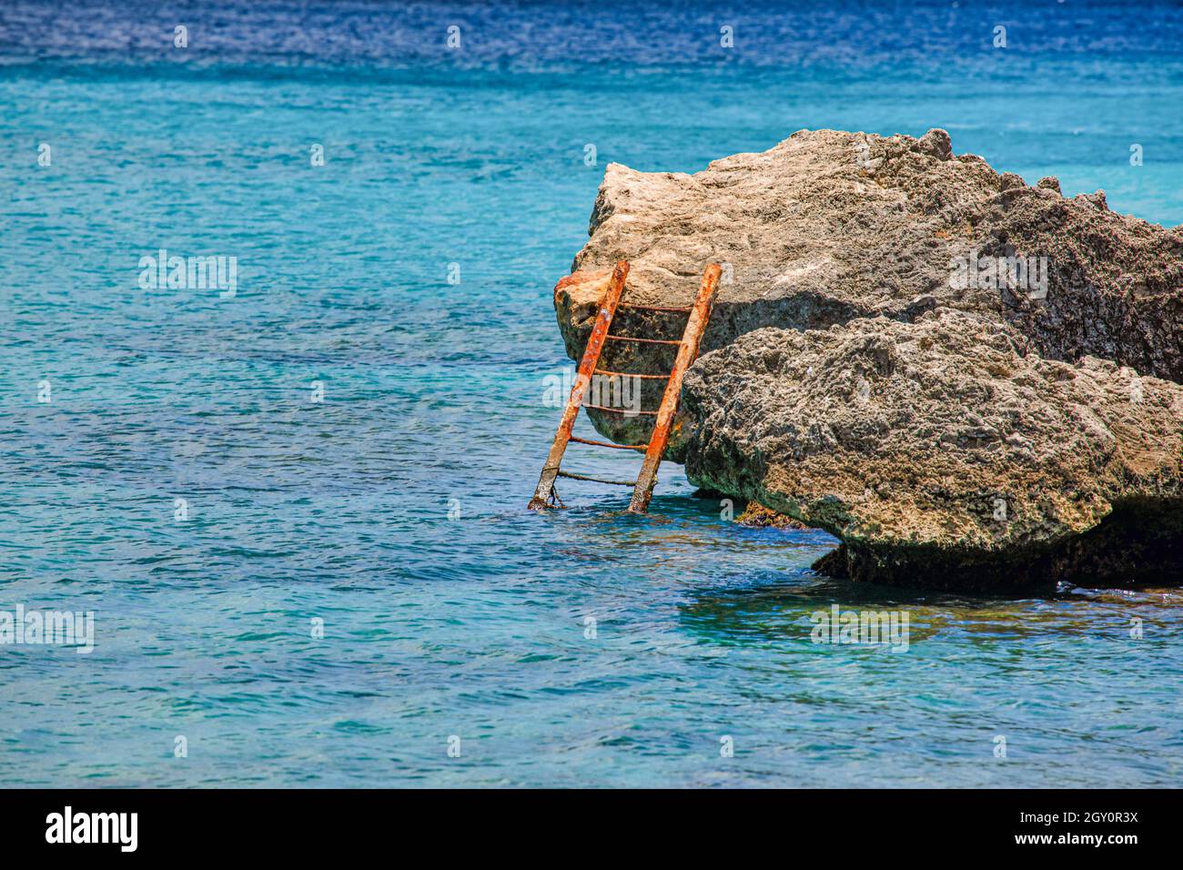 Rusty old ladder in the sea leaning on a stone Stock Photo - Alamy