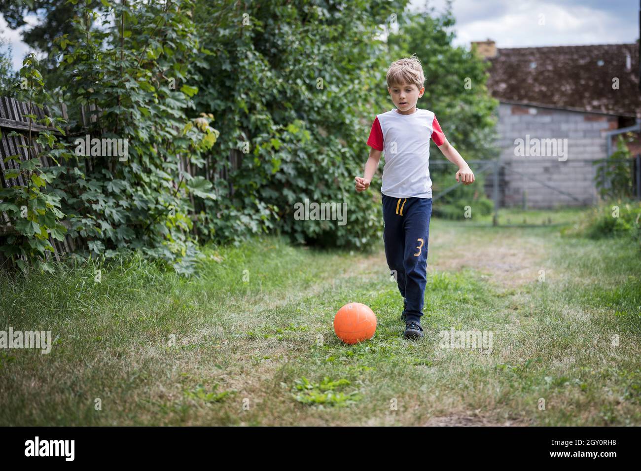 Young boy playing soccer in the backyard during sommer day Stock Photo ...