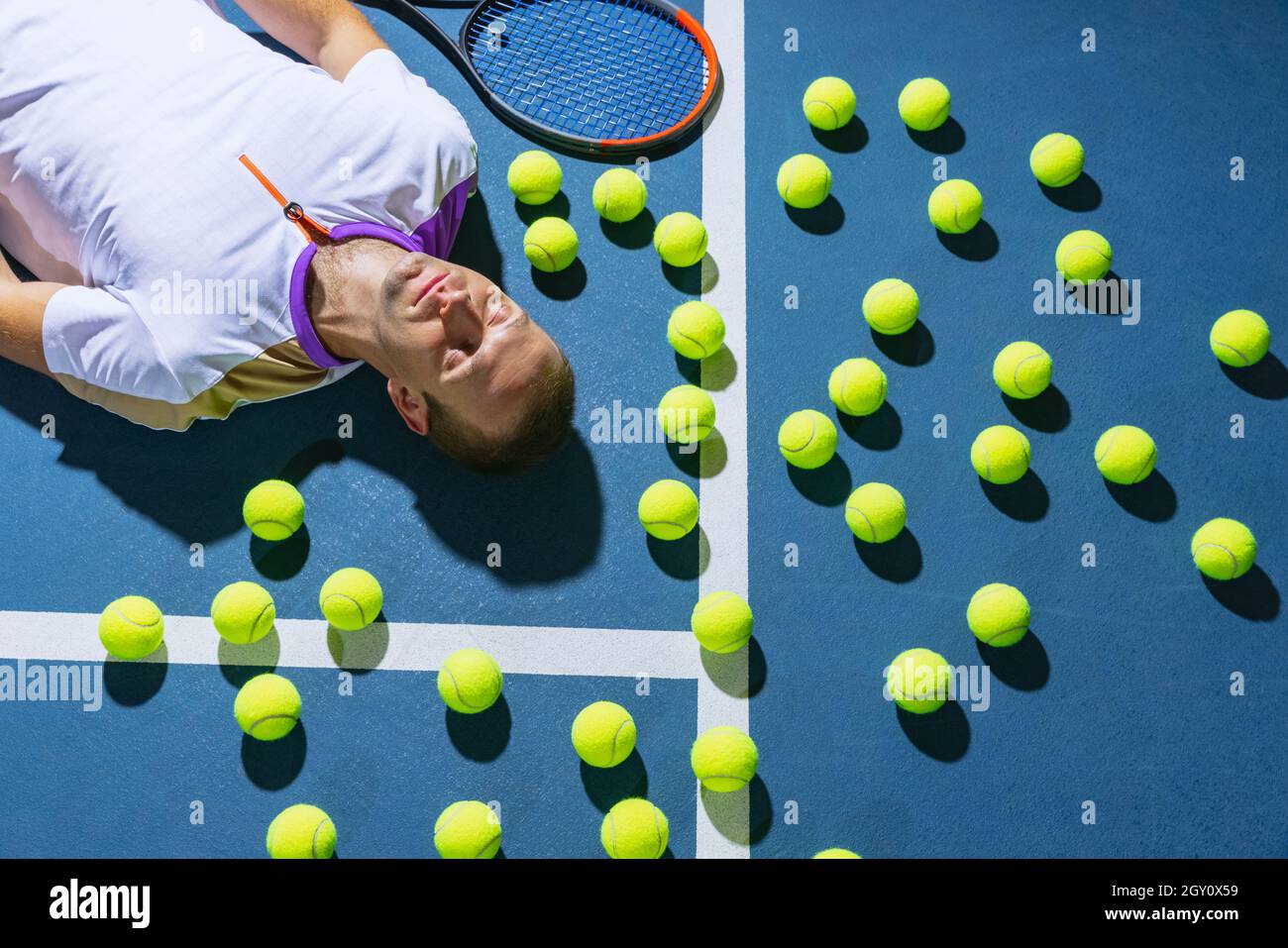 Cropped portrait of male tennis player lying on court floor surrounded ...