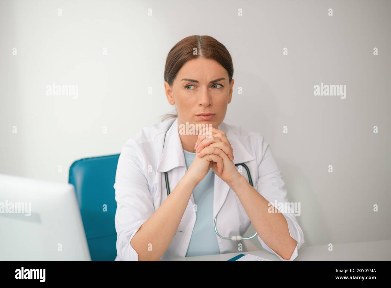 A good-looking female doctor in white robe looking thoughtful Stock ...