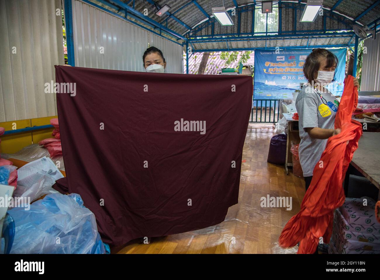 A woman holds a material for sewing a personal protective equipment ...
