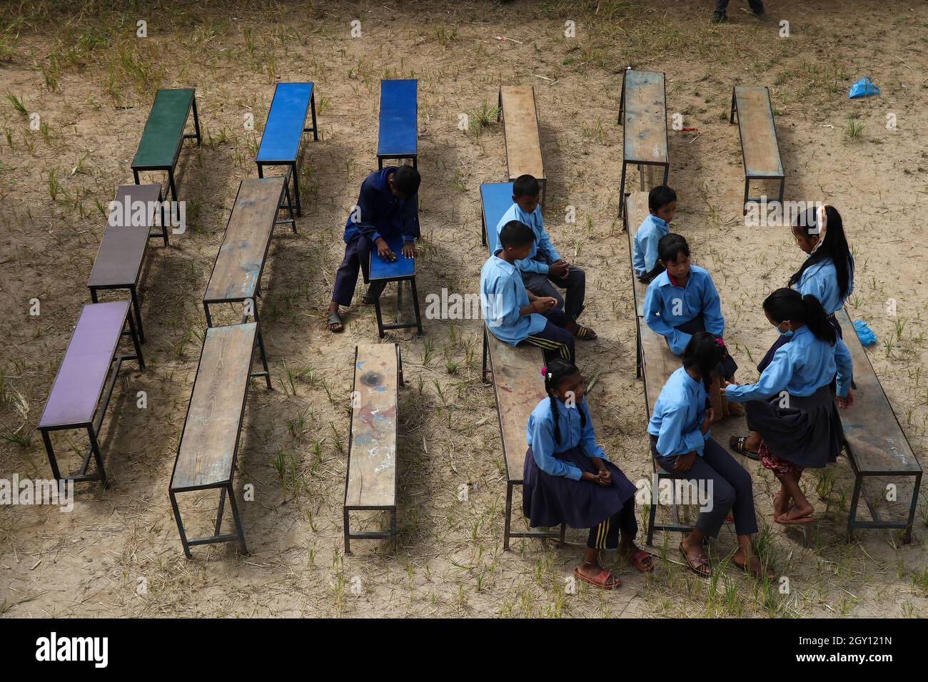 Kathmandu, NE, Nepal. 6th Oct, 2021. Students sit on benches kept in an open ground adhering the ...