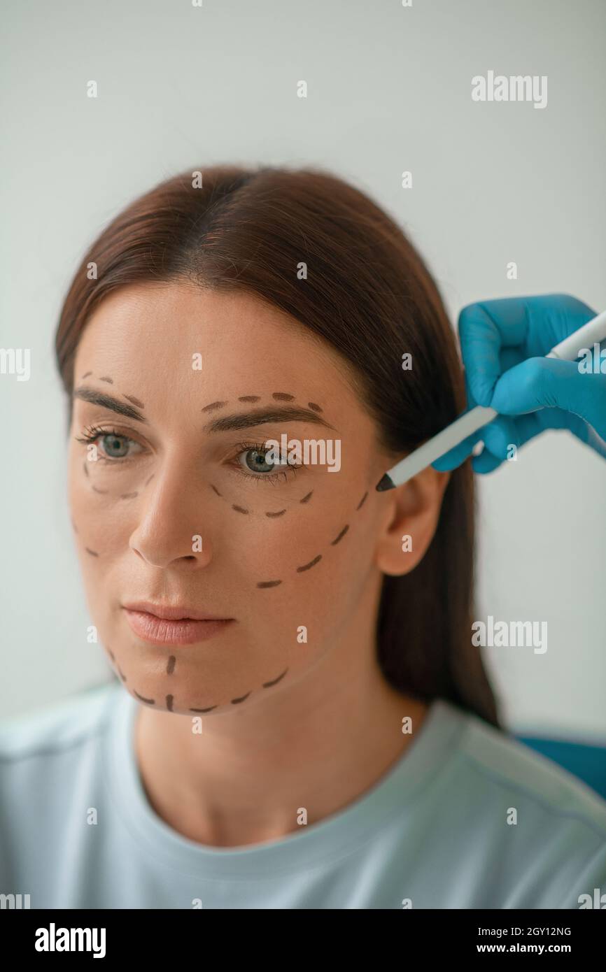 Beautician drawing lines on a womans face Stock Photo - Alamy