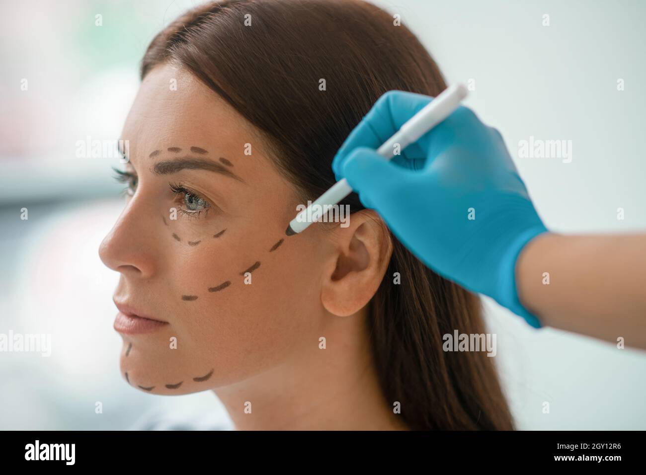 Beautician drawing lines on a womans face Stock Photo - Alamy